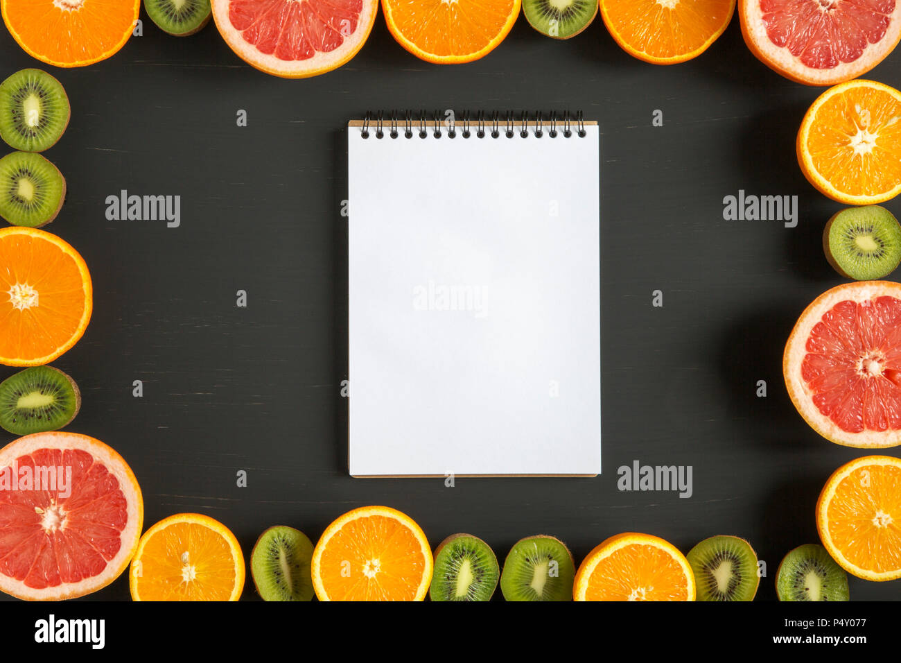 Flat lay. Top view. Notebook with sliced colorful fresh fruits: kiwi ...