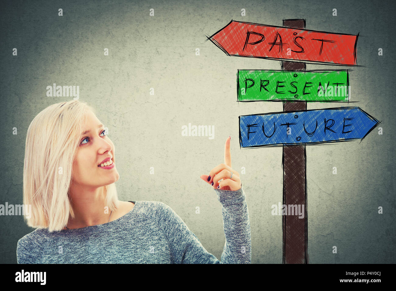 Young cheerful businesswoman pointing finger to a signpost choosing ...