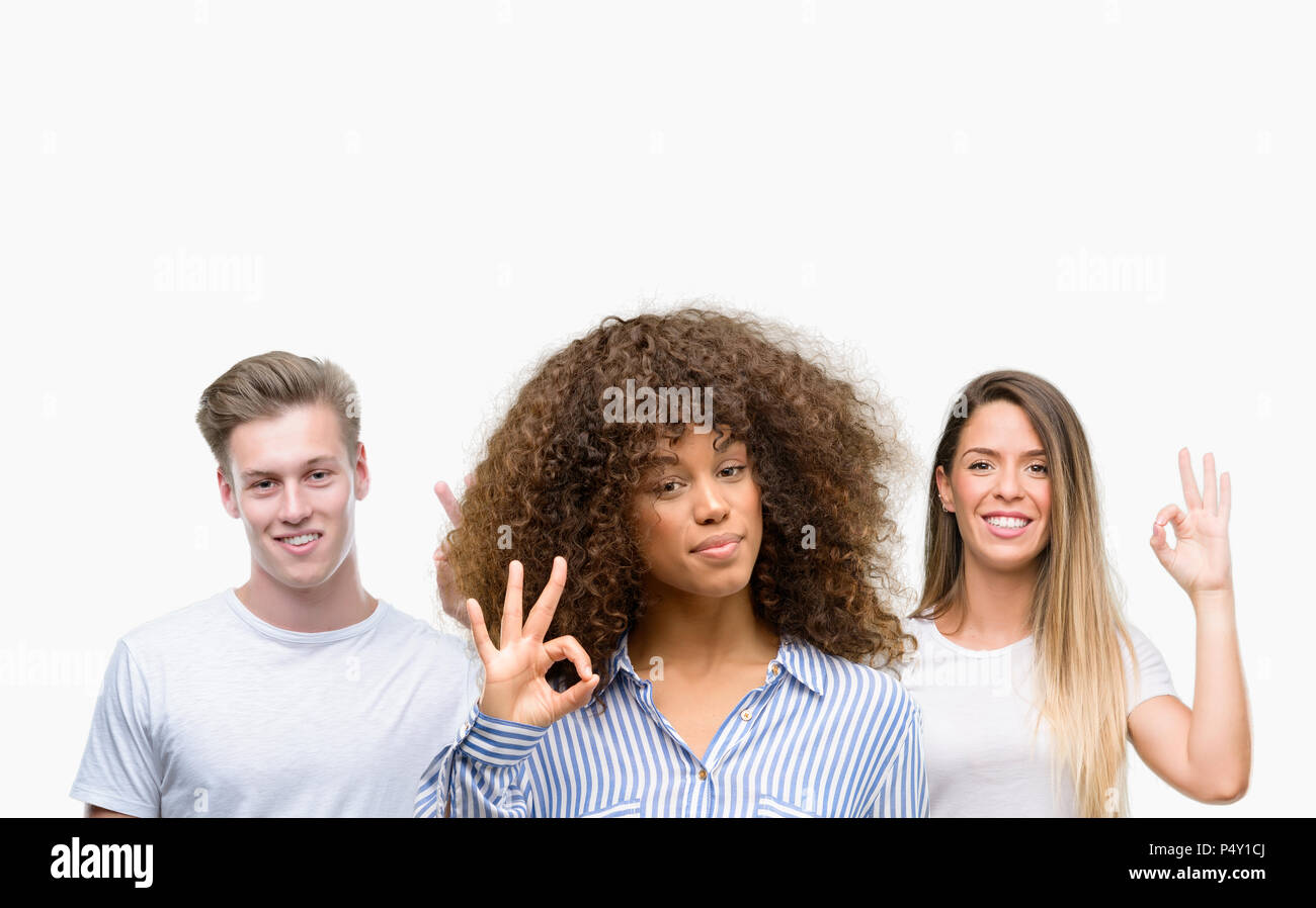 Group of young people over white background doing ok sign with fingers ...