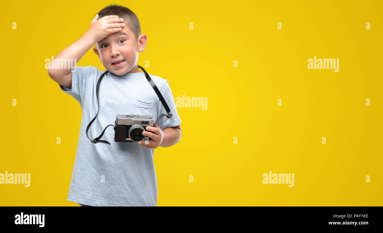 Dark haired little child holding vintage camera stressed with hand on ...
