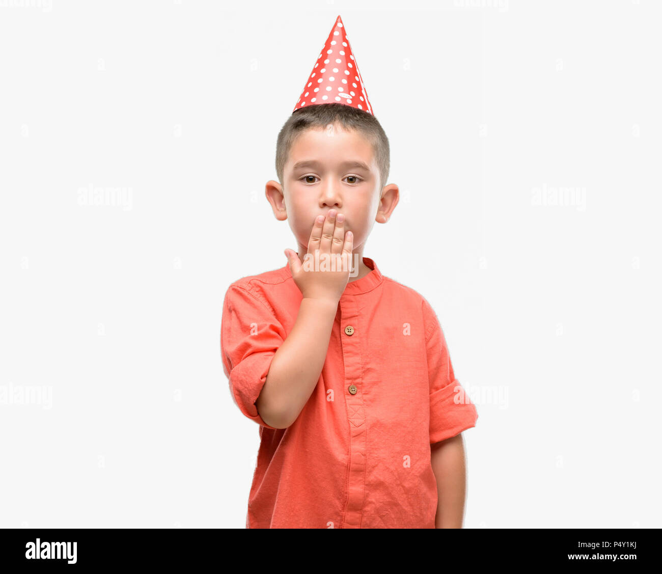 Dark haired little child wearing birthday cap cover mouth with hand ...