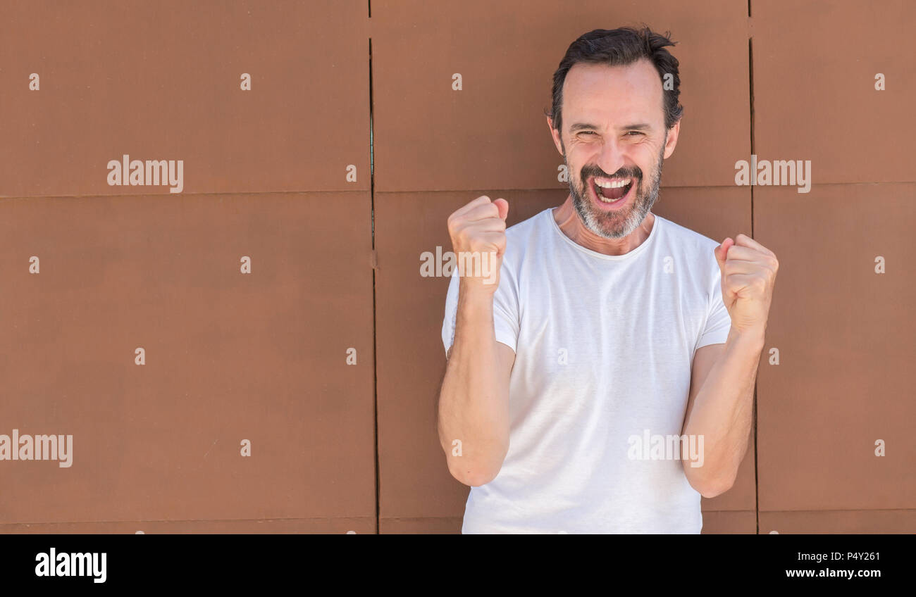 Handsome senior man standing over wall screaming proud and celebrating ...