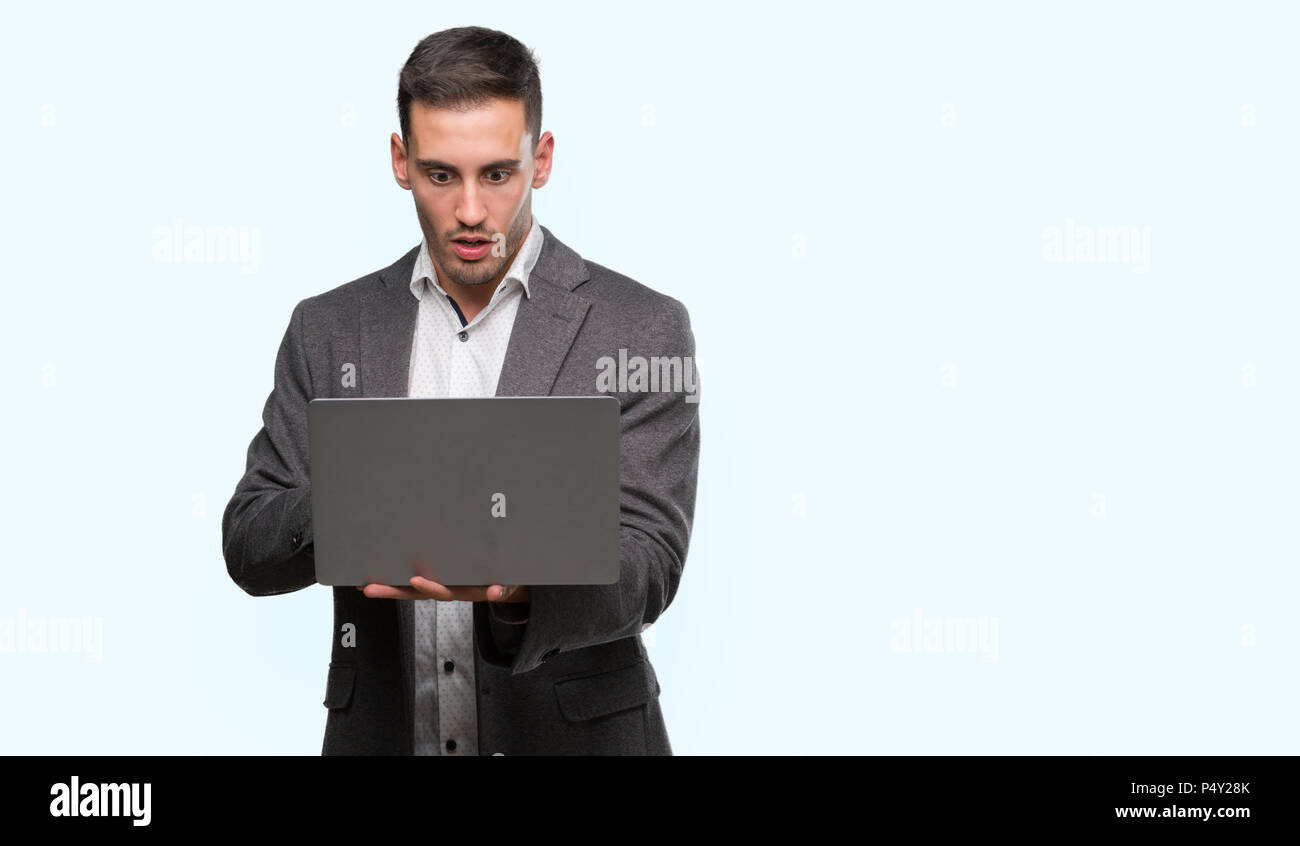 Handsome young man using computer laptop scared in shock with a ...