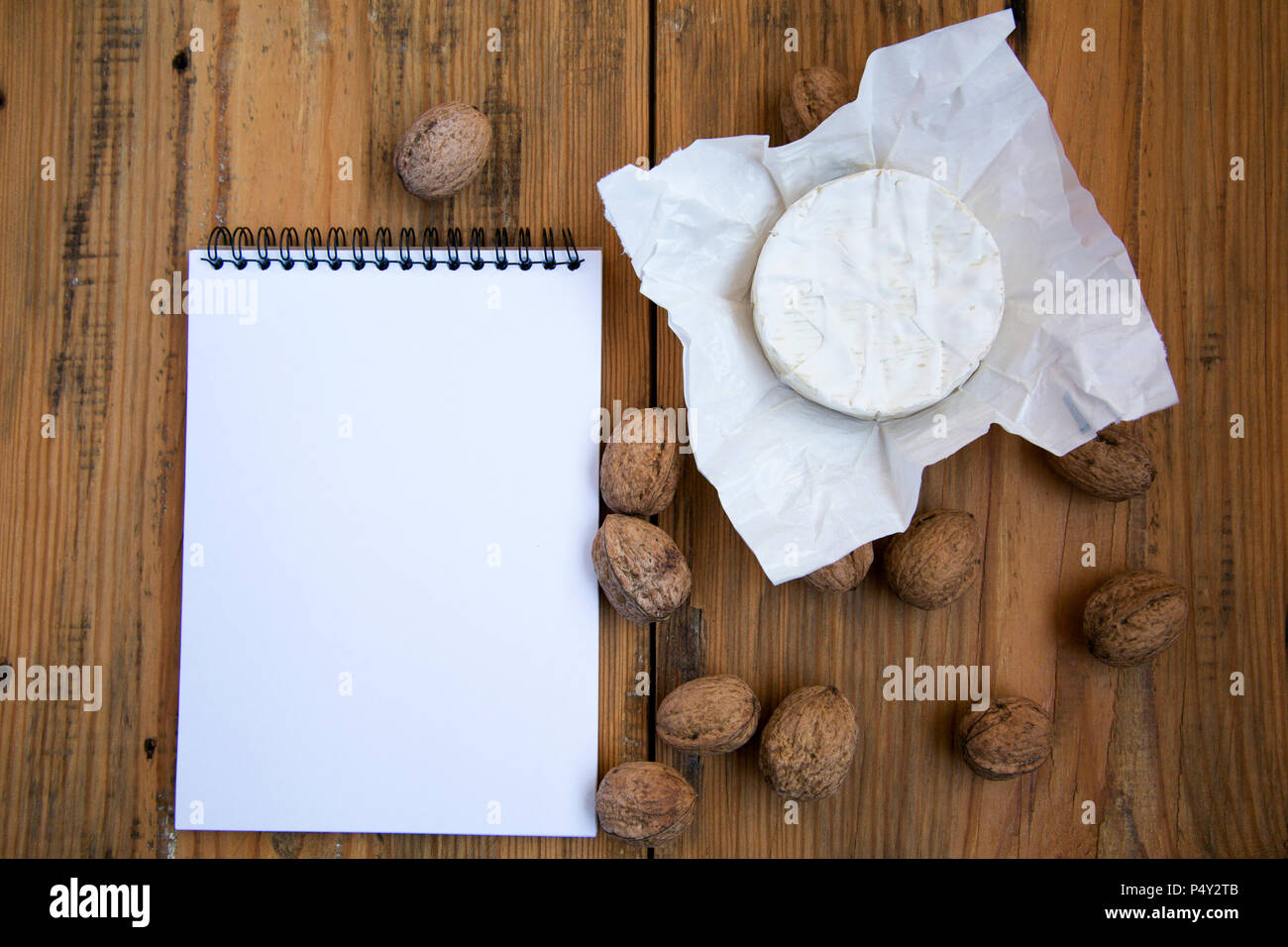 Cheese camembert or brie on wooden board with walnuts and notebook ...