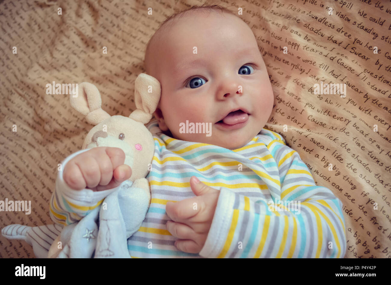 Beautiful baby hags a toy mouse and shows tongue Stock Photo - Alamy