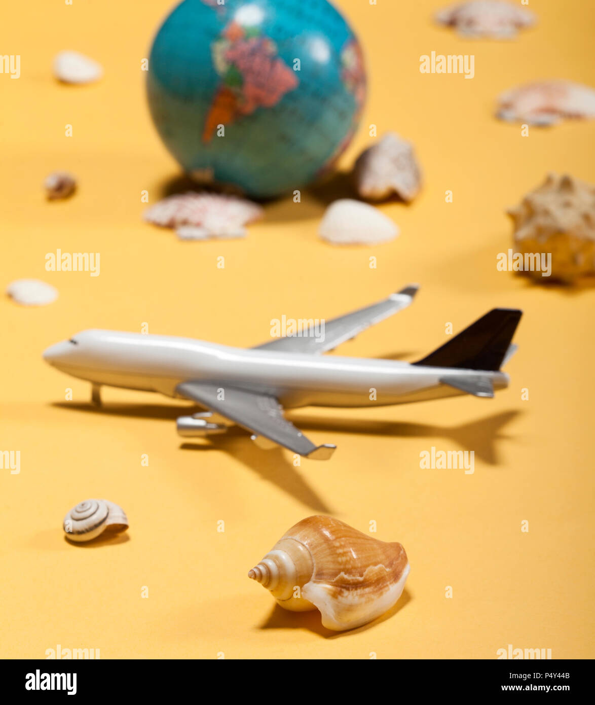 Travel concept background. Globe, airplane and shells on yellow ...