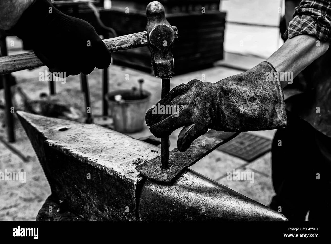 Blacksmith working a glowing iron in an old forge Black and White Stock ...