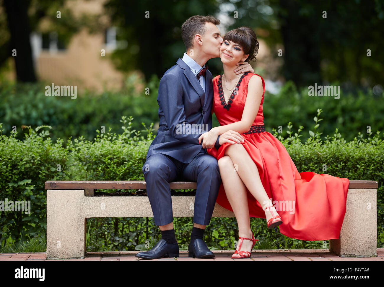 Young couple sitting on a bench and kissing Stock Photo - Alamy