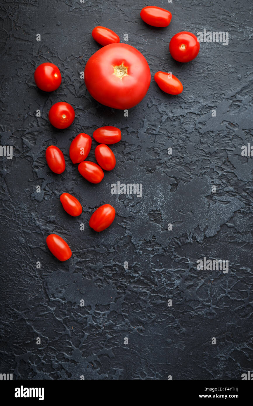 Fresh raw juicy tomatoes of different sizes on a black background Stock ...