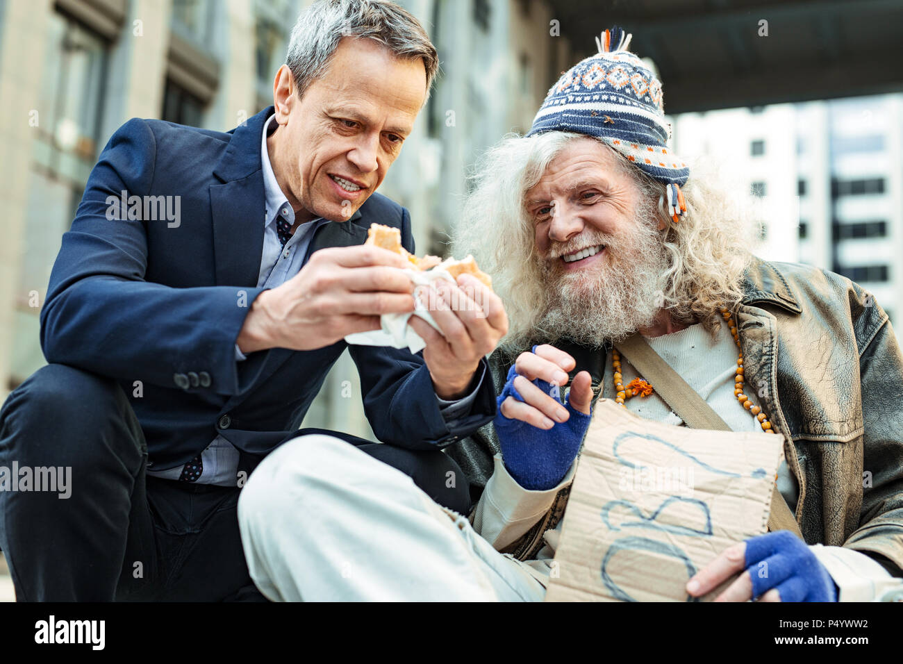 Smiling homeless elderly man eating burger from stranger Stock Photo ...