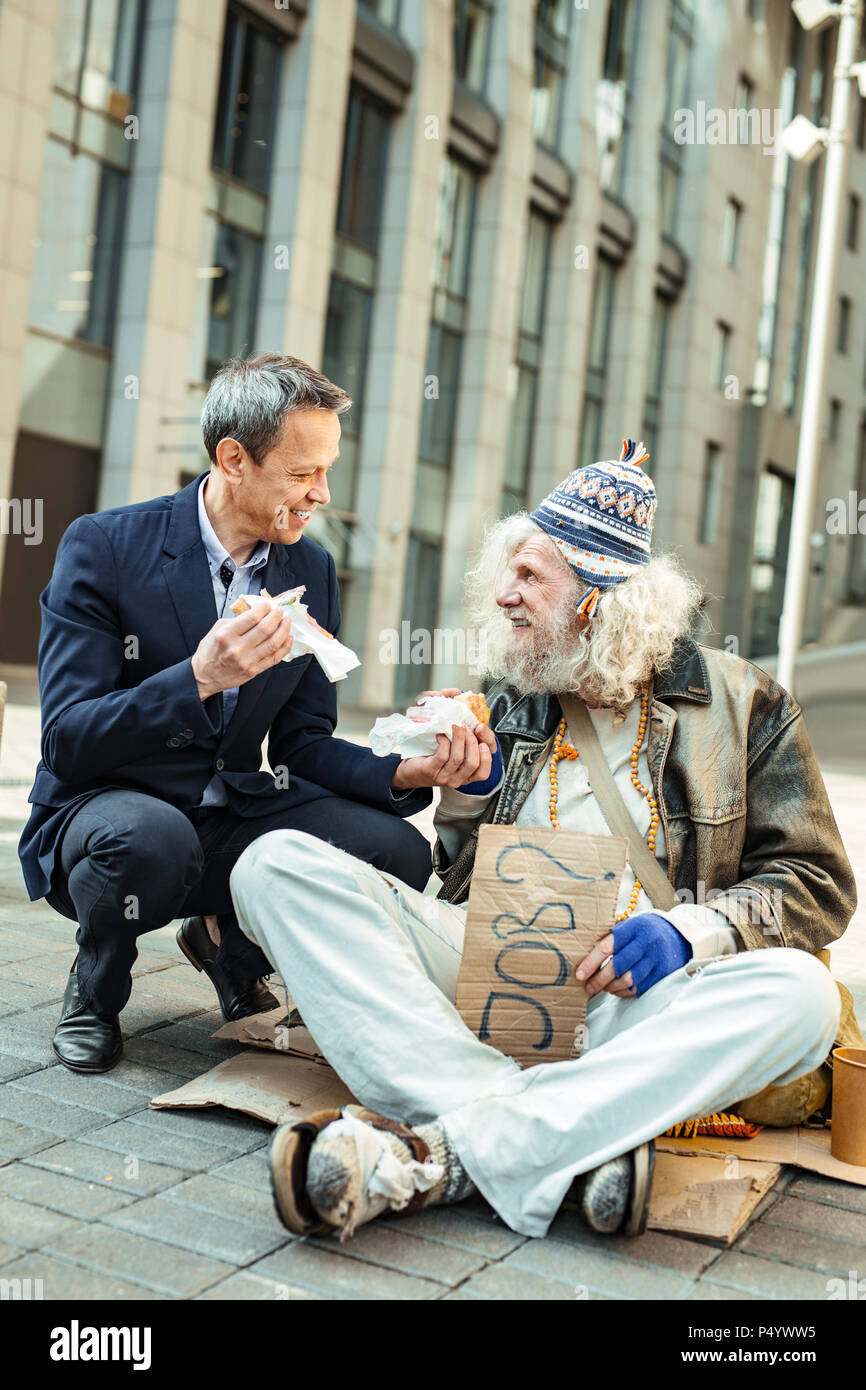Elderly hippy wearing bright cap receiving food from stranger Stock ...