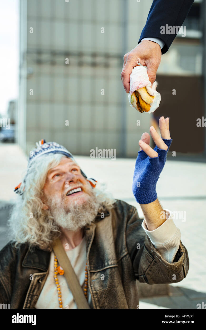 Homeless man taking burger from kind stranger Stock Photo - Alamy