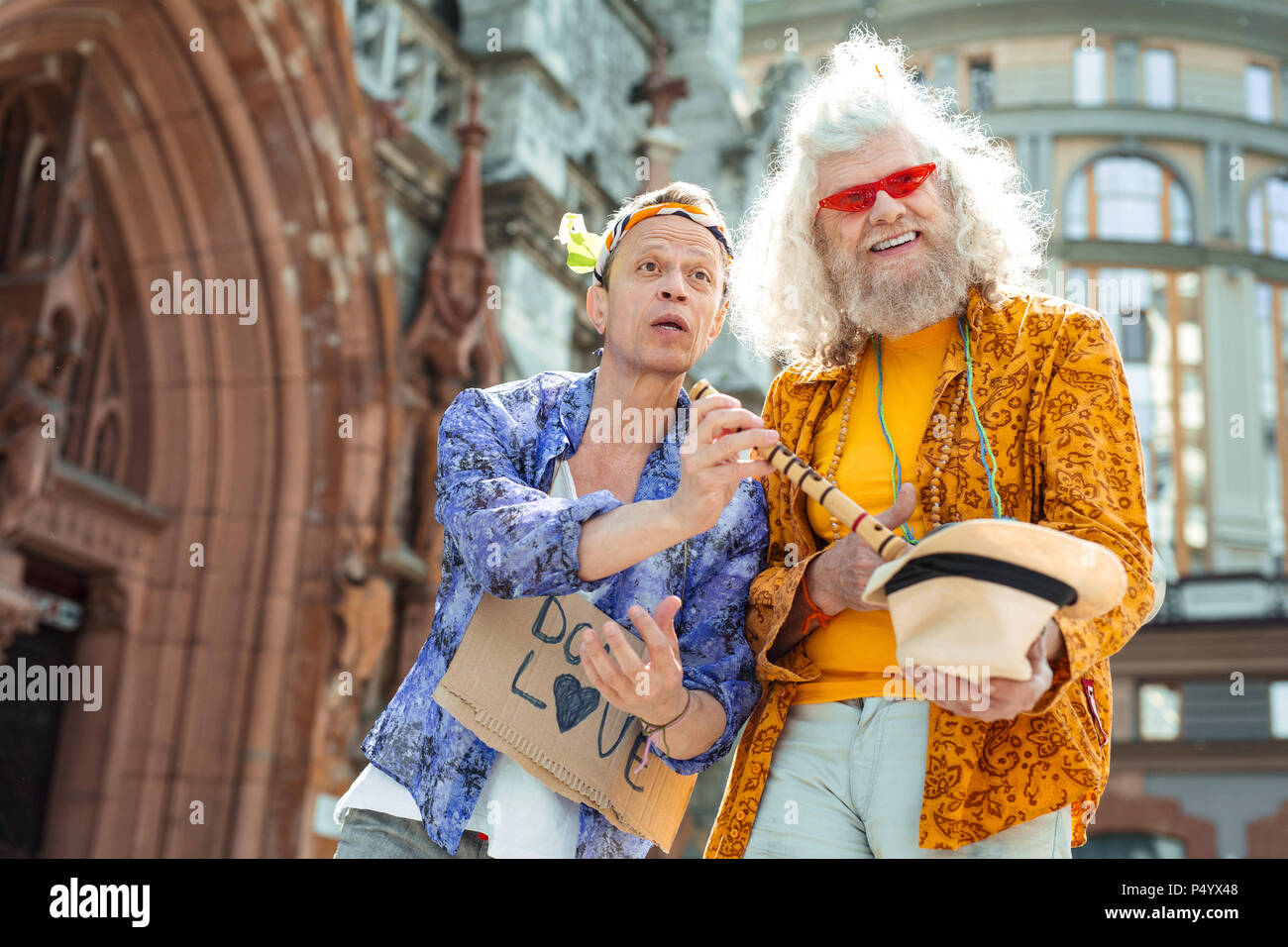 Two smiling hippies interacting with people during their performance ...