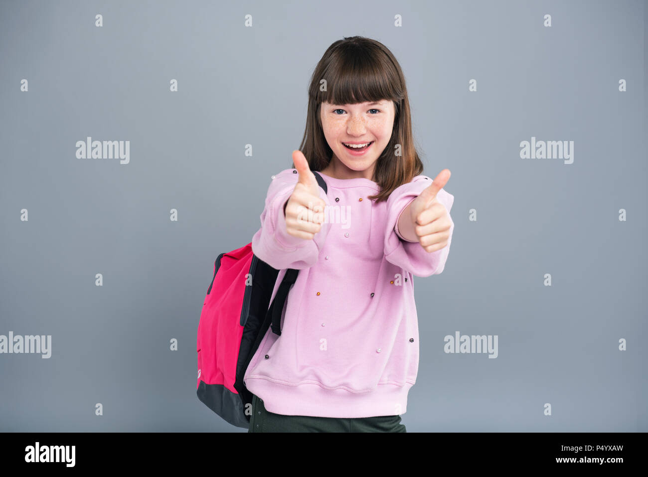 Upbeat teenage schoolgirl showing thumbs up Stock Photo - Alamy