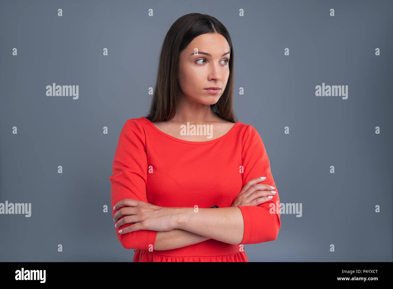 Beautiful young woman in red dress crossing her arms Stock Photo - Alamy