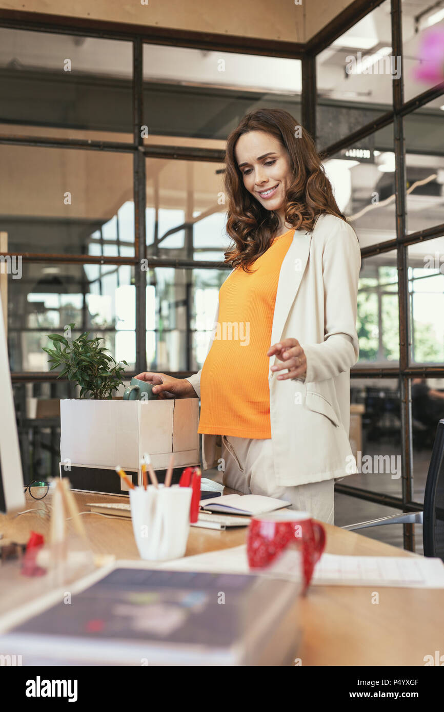 Beautiful pregnant employee gathering belongings Stock Photo - Alamy