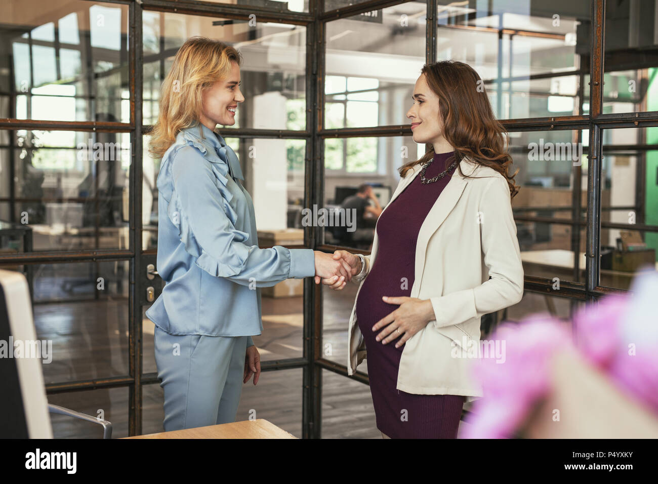 Positive pregnant CEO greeting colleague Stock Photo - Alamy