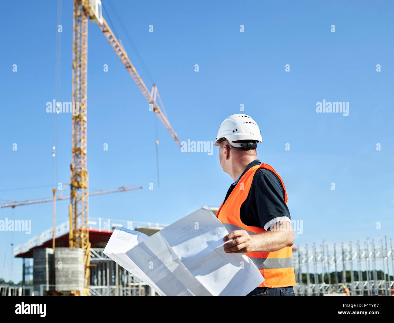 Construction worker with blueprint on construction site Stock Photo - Alamy