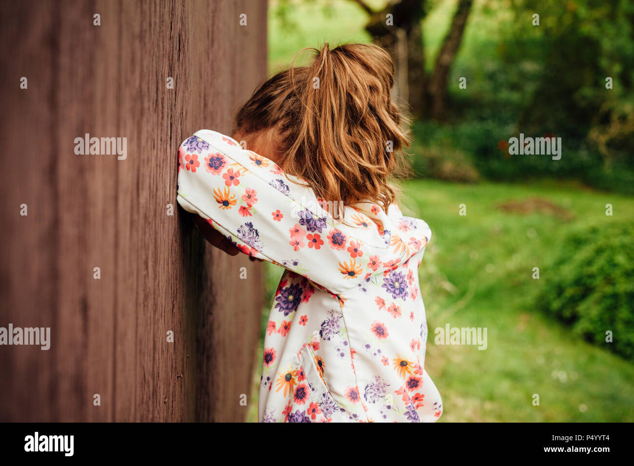 Girl leaning against wooden wall hiding her face Stock Photo - Alamy