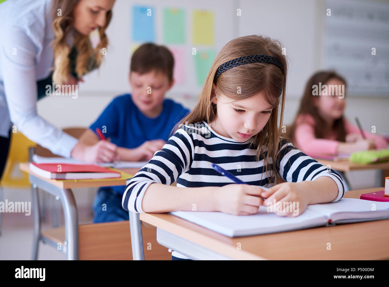 Schoolgirl writing in exercise book in class Stock Photo - Alamy