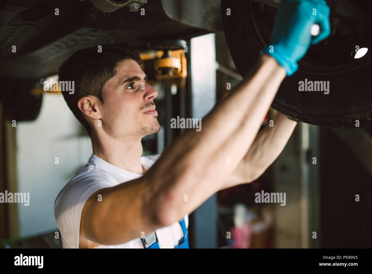 Mechanic working on the underbody of a car in a workshop Stock Photo ...