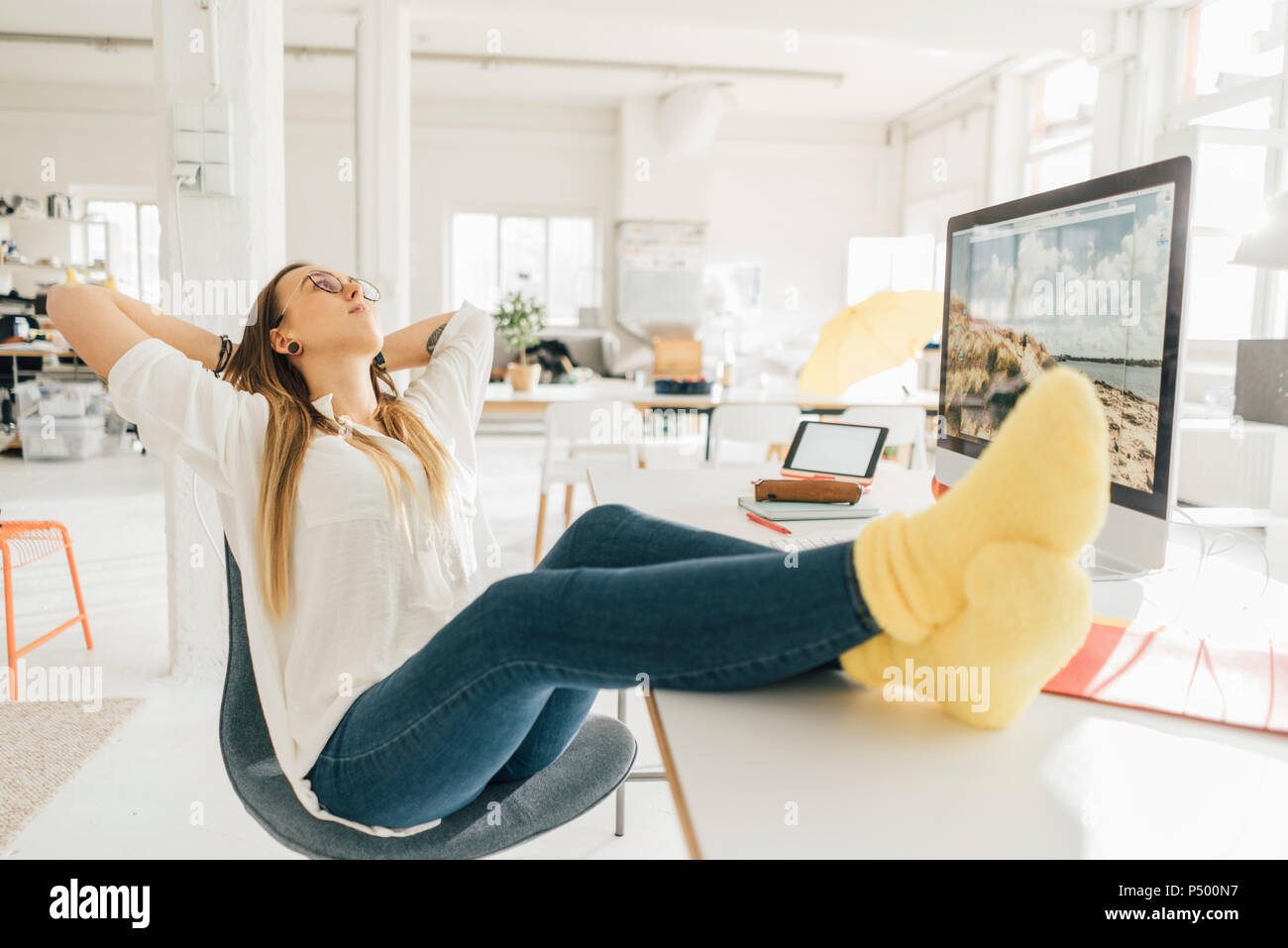 Young freelancer relaxing with feet up at desk in a loft Stock Photo ...