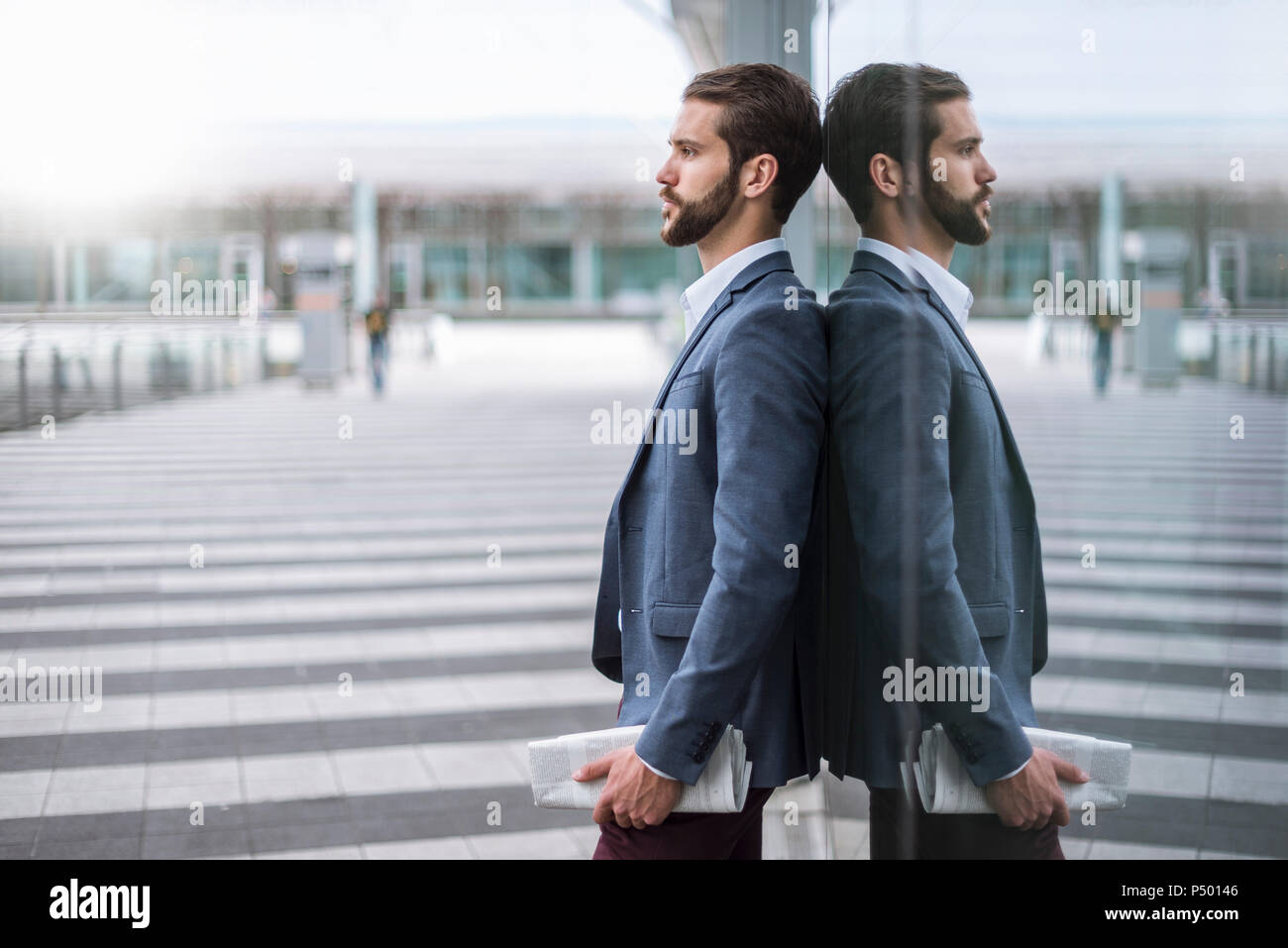 Young businessman leaning at building with glass facade Stock Photo - Alamy