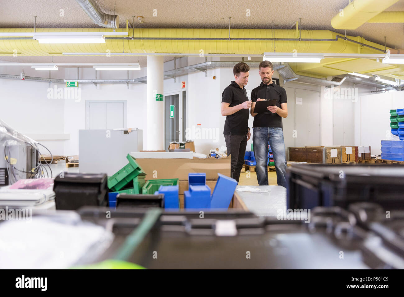 Two men with clipboard talking in factory Stock Photo - Alamy