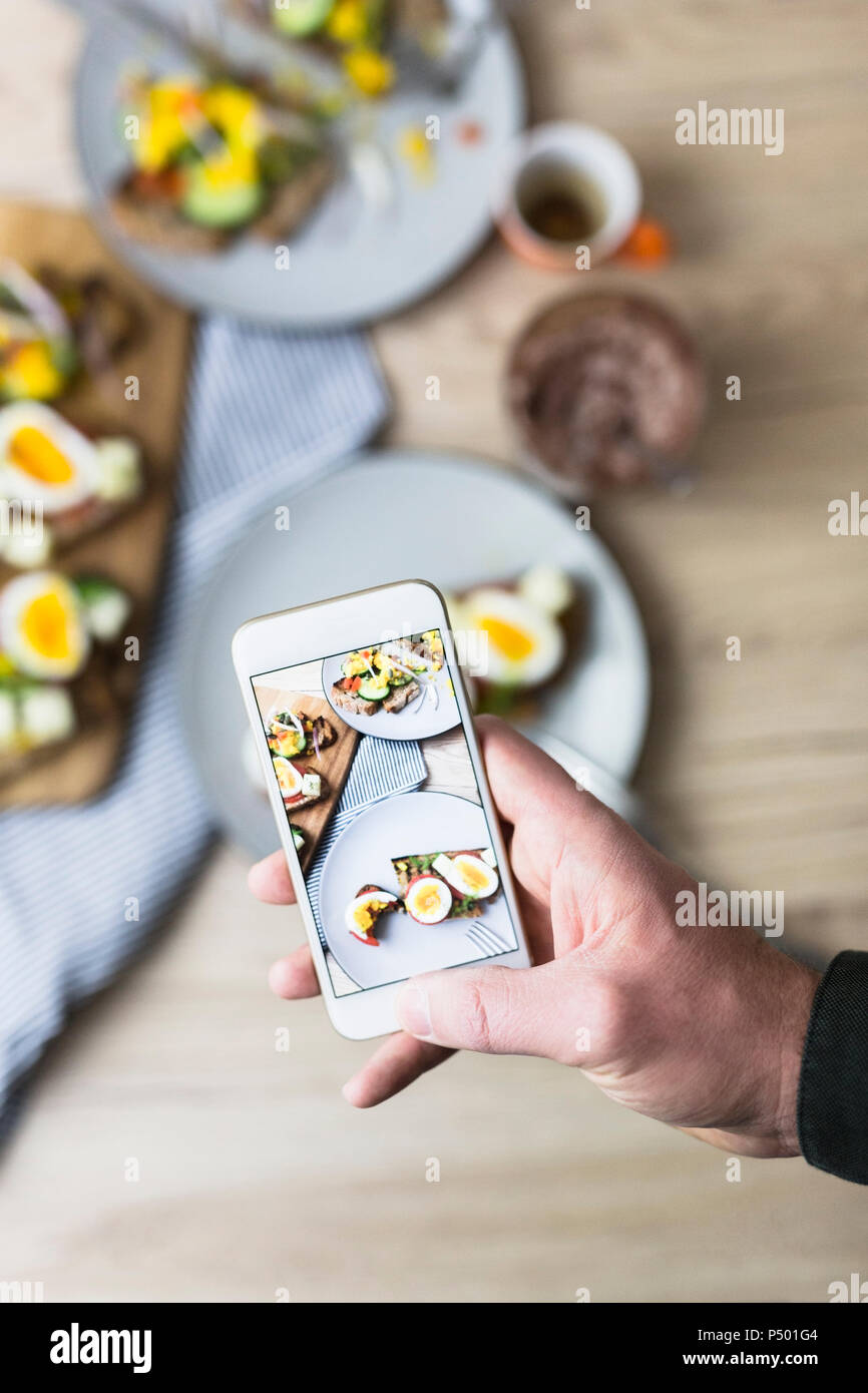 Man holding smartphone with photo of vegetarian breakfast with bread ...