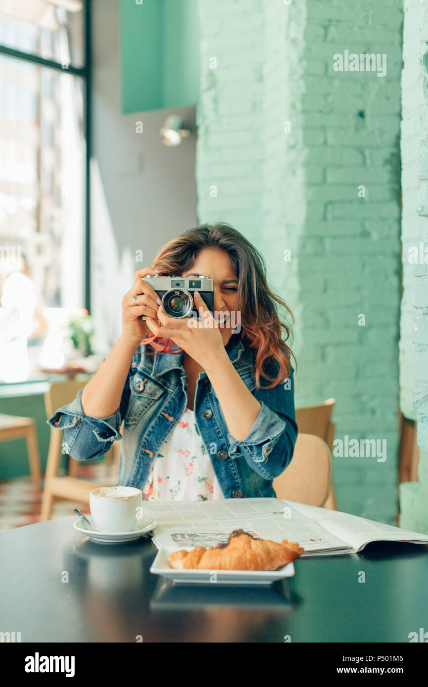 Laughing woman sitting at coffee shop taking pictures with camera Stock ...