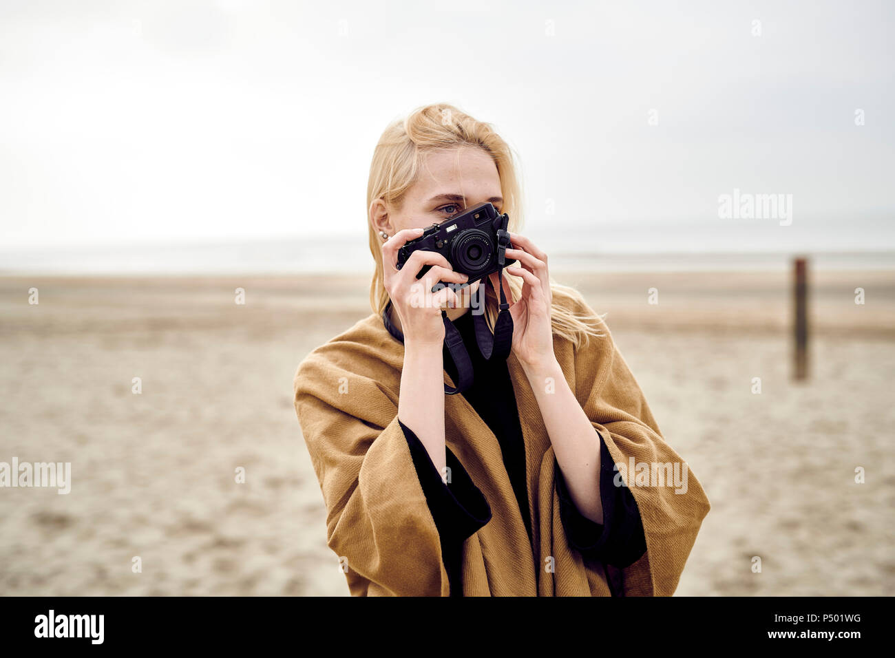 Blond young woman taking photo camera beach hi-res stock photography ...