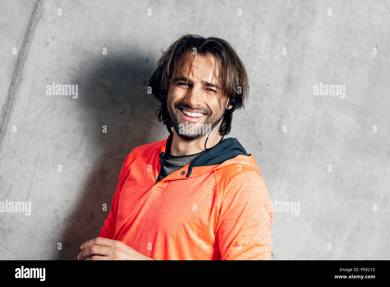 Portrait of smiling athlete at concrete wall Stock Photo - Alamy