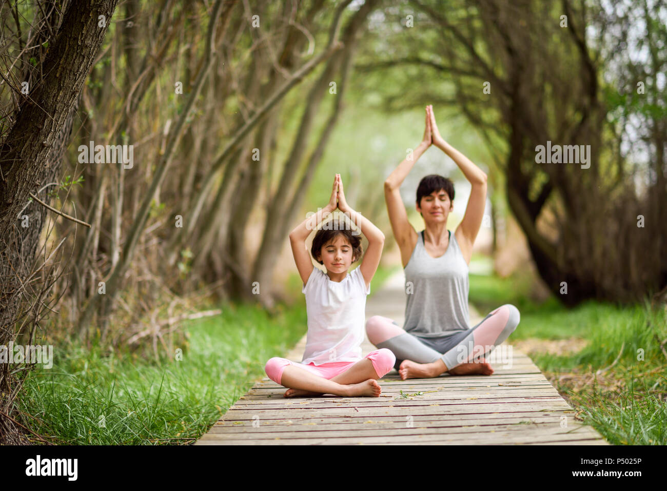 Mother and daughter doing yoga on boardwalk Stock Photo - Alamy