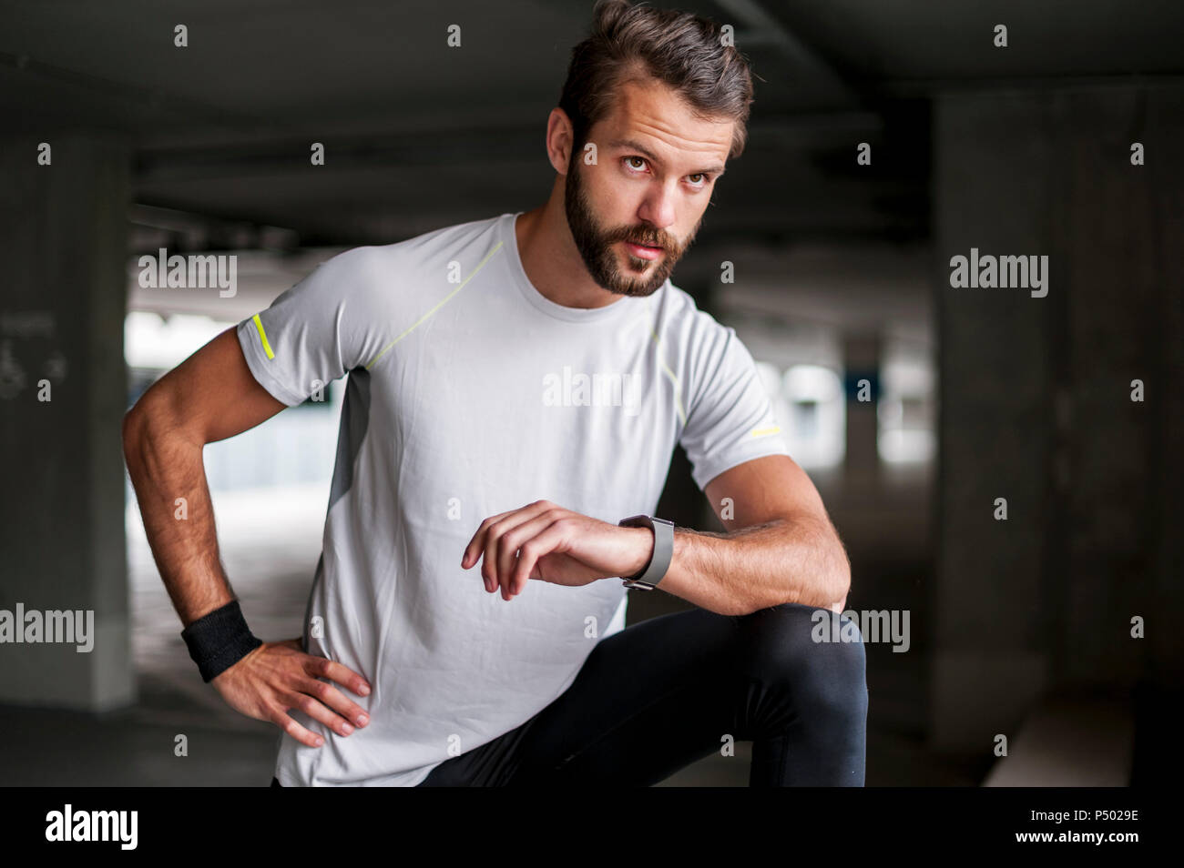 Athlete in parking garage with smartwatch Stock Photo - Alamy