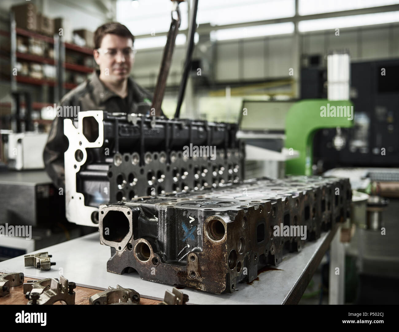Worker in metalworking factory lifting cylinder head with crane Stock ...