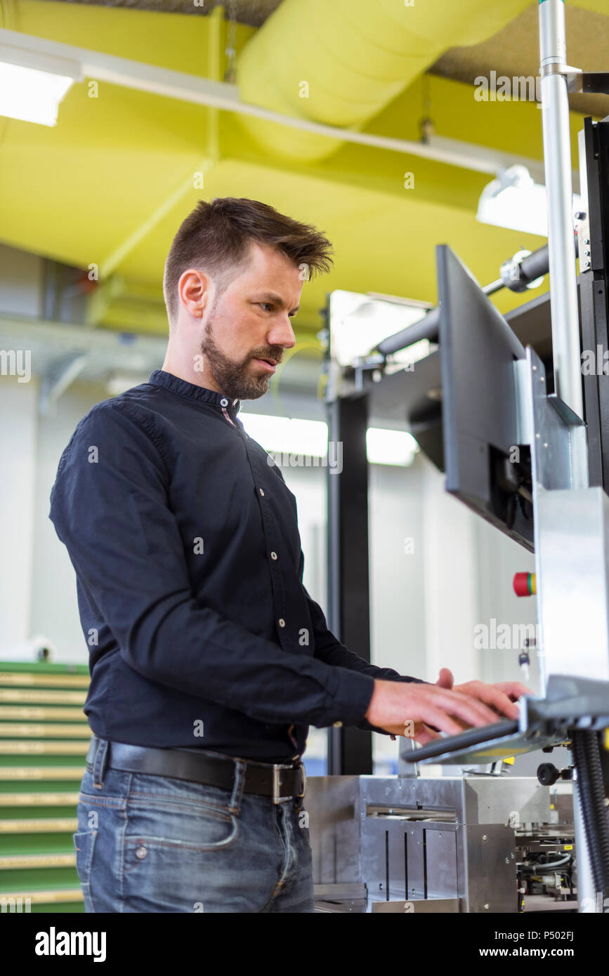 Man in factory operating machine Stock Photo - Alamy