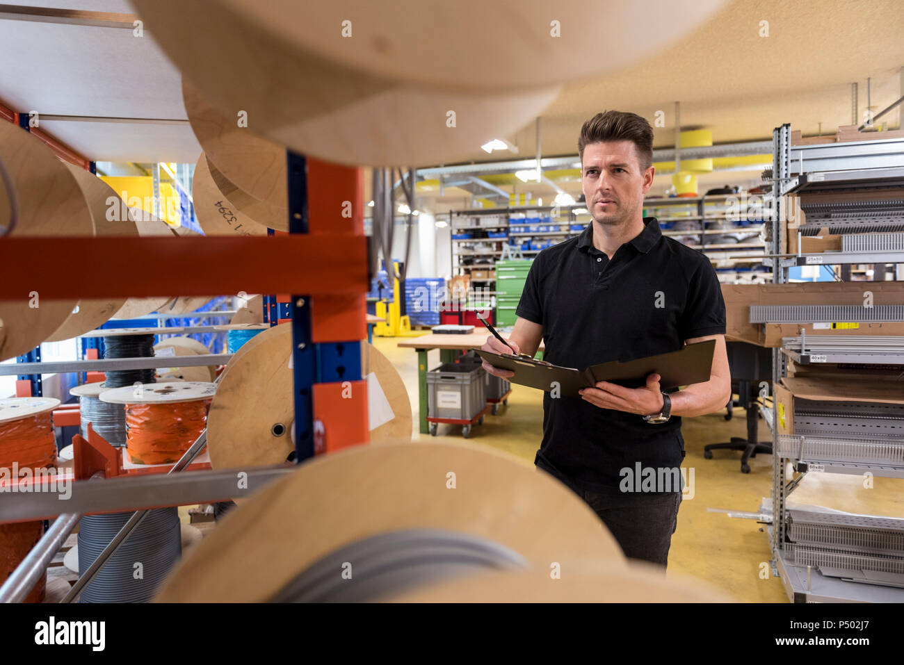 Man with clipboard in factory taking notes Stock Photo - Alamy