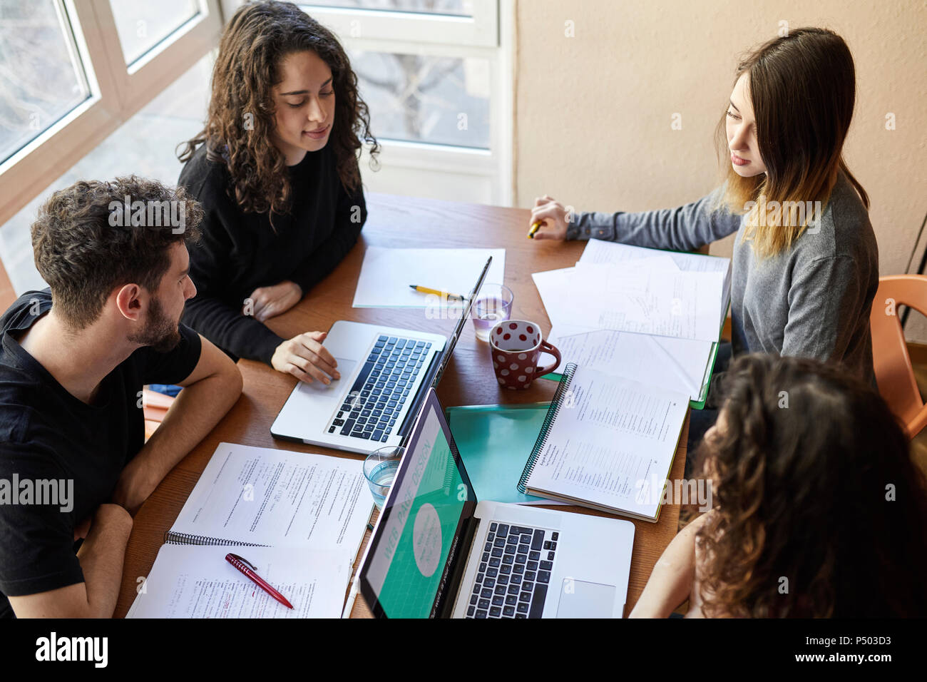 Four students at desk working and learning together Stock Photo - Alamy