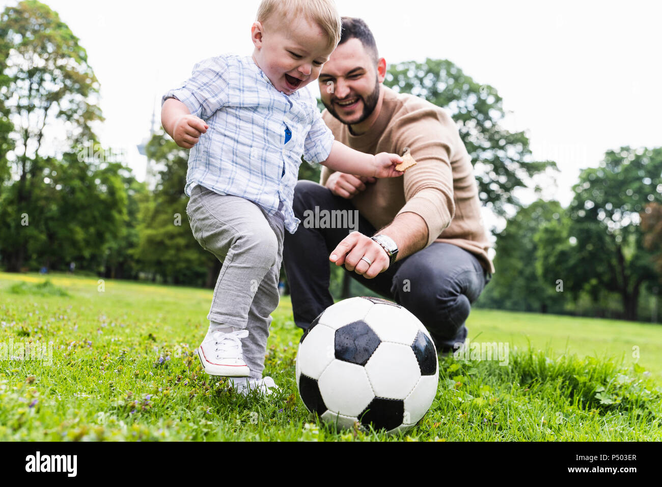 Happy father playing football with son in a park Stock Photo - Alamy