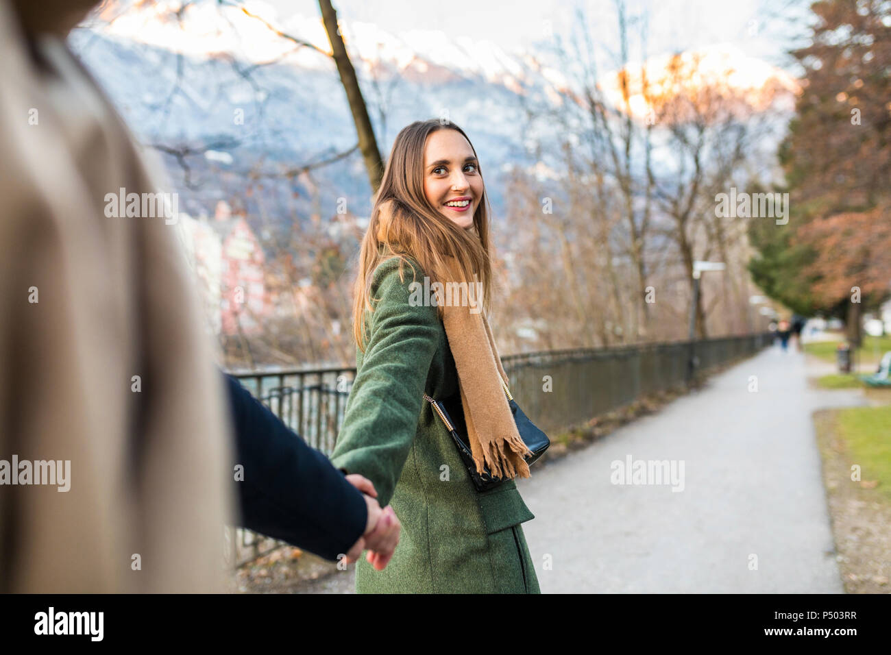 Austria, Innsbruck, portrait of happy young woman strolling hand in ...