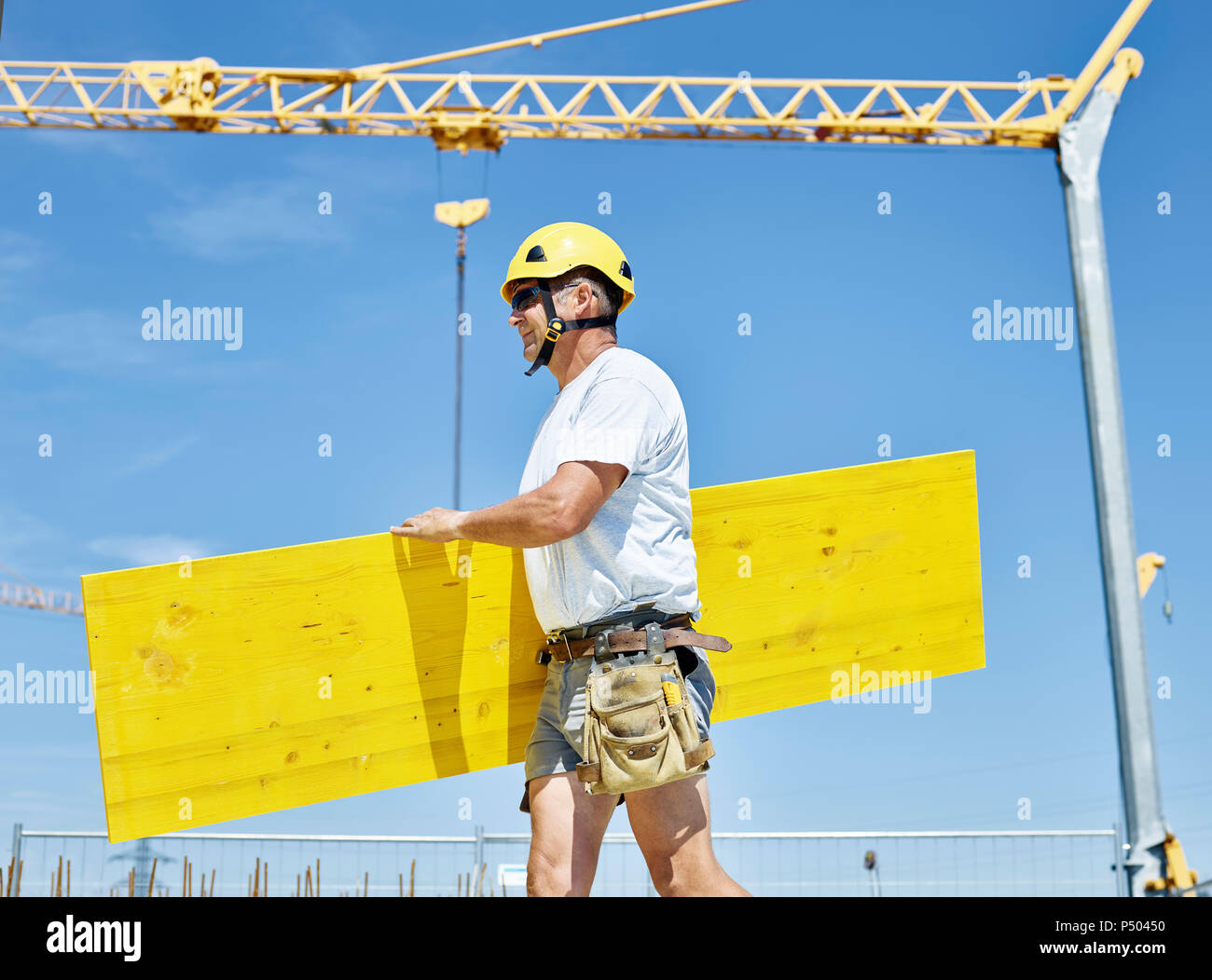 Construction worker carrying plywood construction site Stock Photo - Alamy