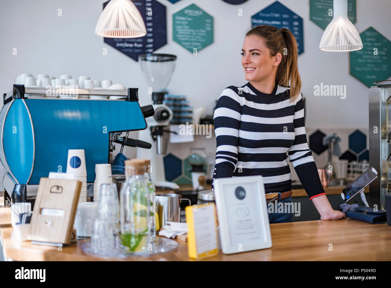Smiling young woman behind the counter of a cafe Stock Photo - Alamy