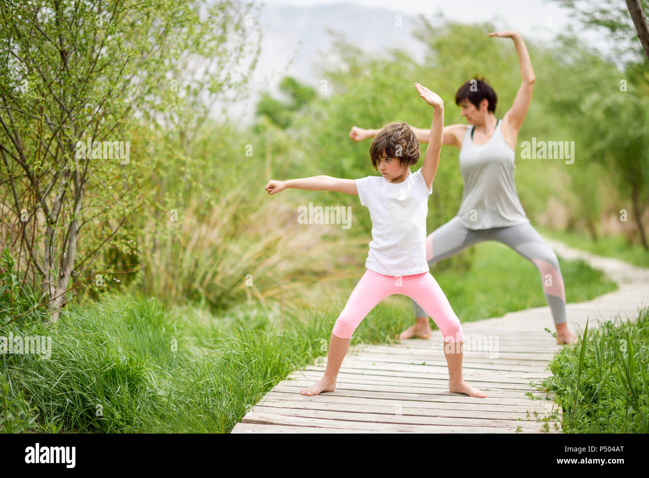 Mother and daughter doing yoga on boardwalk Stock Photo - Alamy