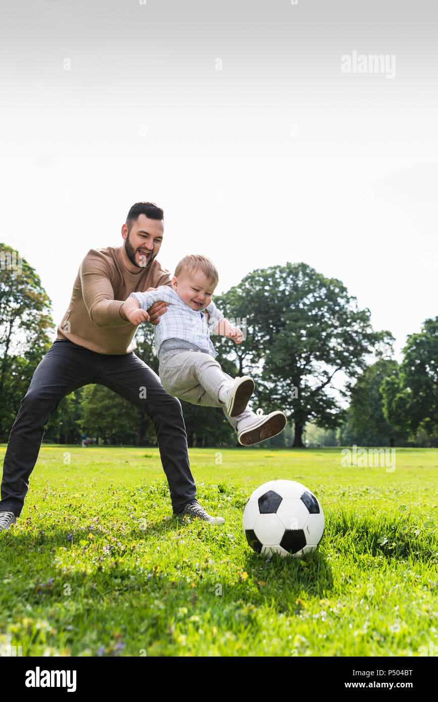 Happy father playing football with son in a park Stock Photo - Alamy
