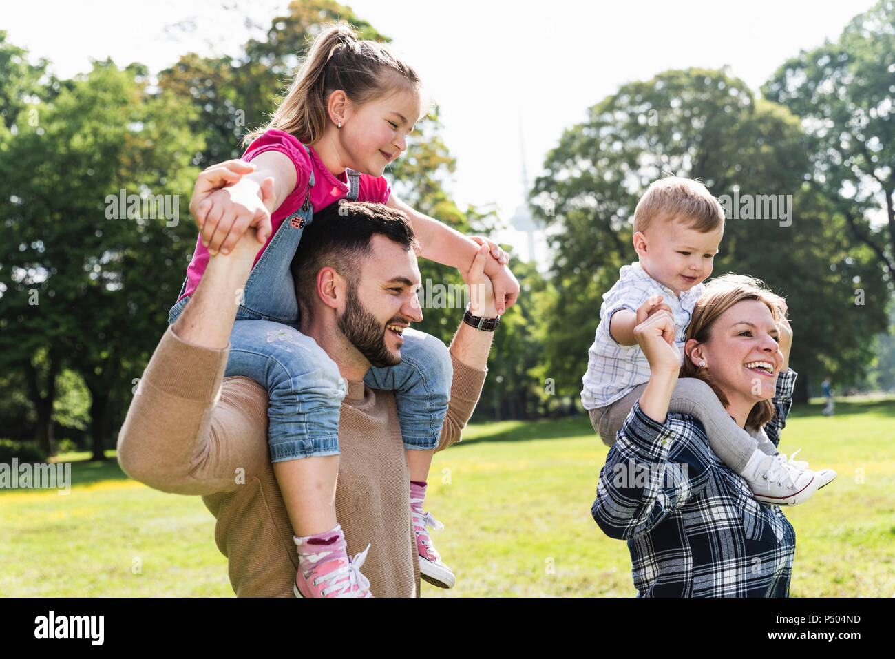 Happy parents carrying children on shoulders in a park Stock Photo - Alamy