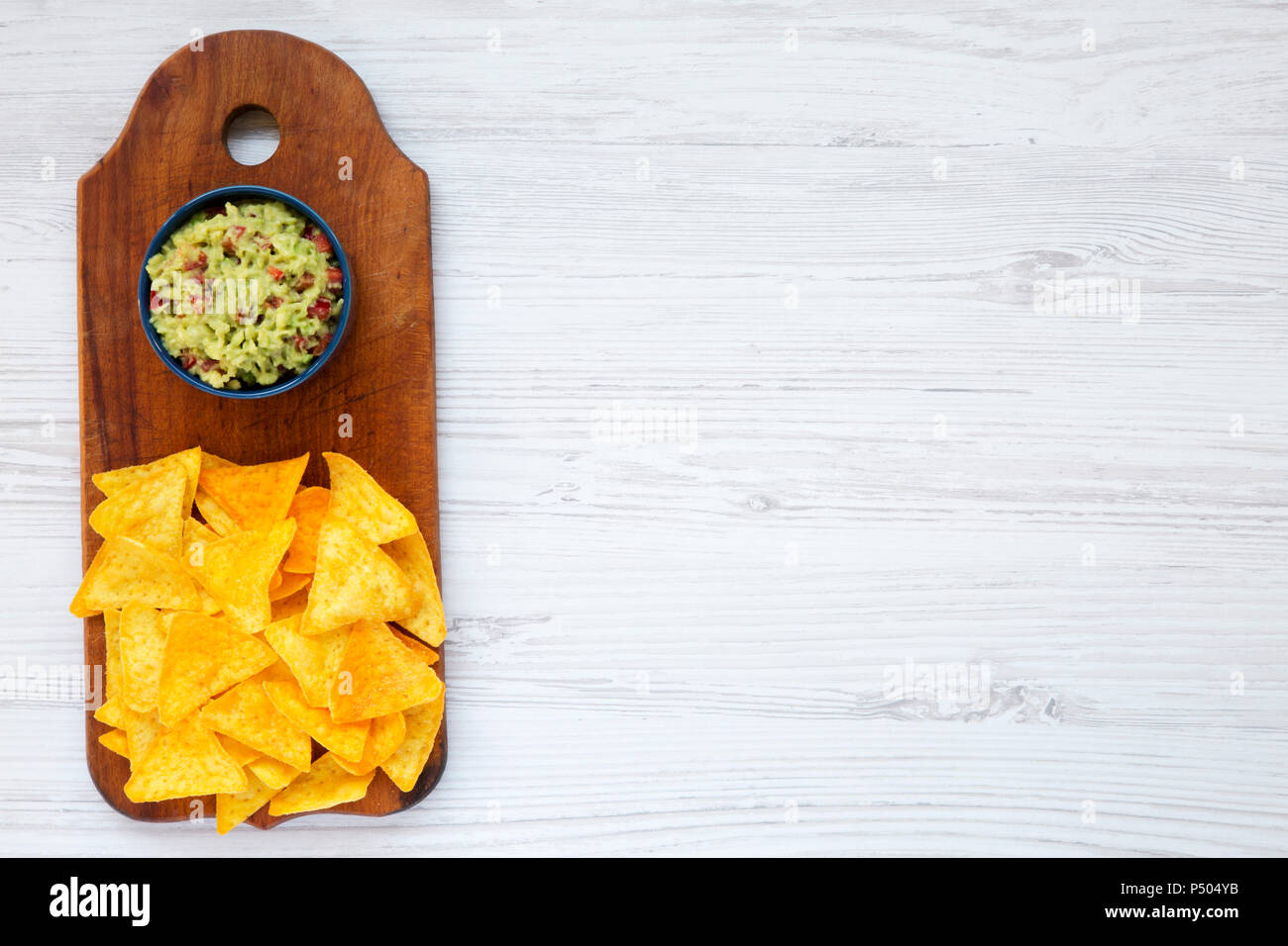 Bowl of guacamole with nachos on wooden board. White wooden background ...