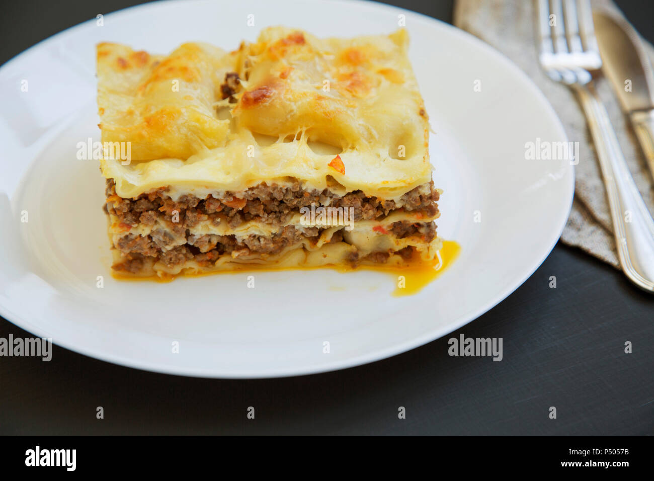 Traditional lasagne served on a white round plate, dark background ...