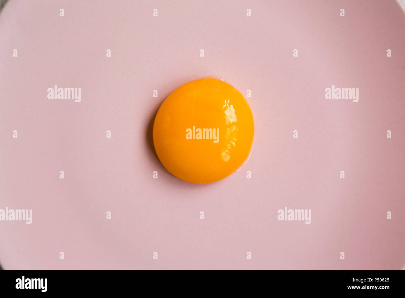 Egg yolk on a pink plate, top view. Closeup Stock Photo - Alamy