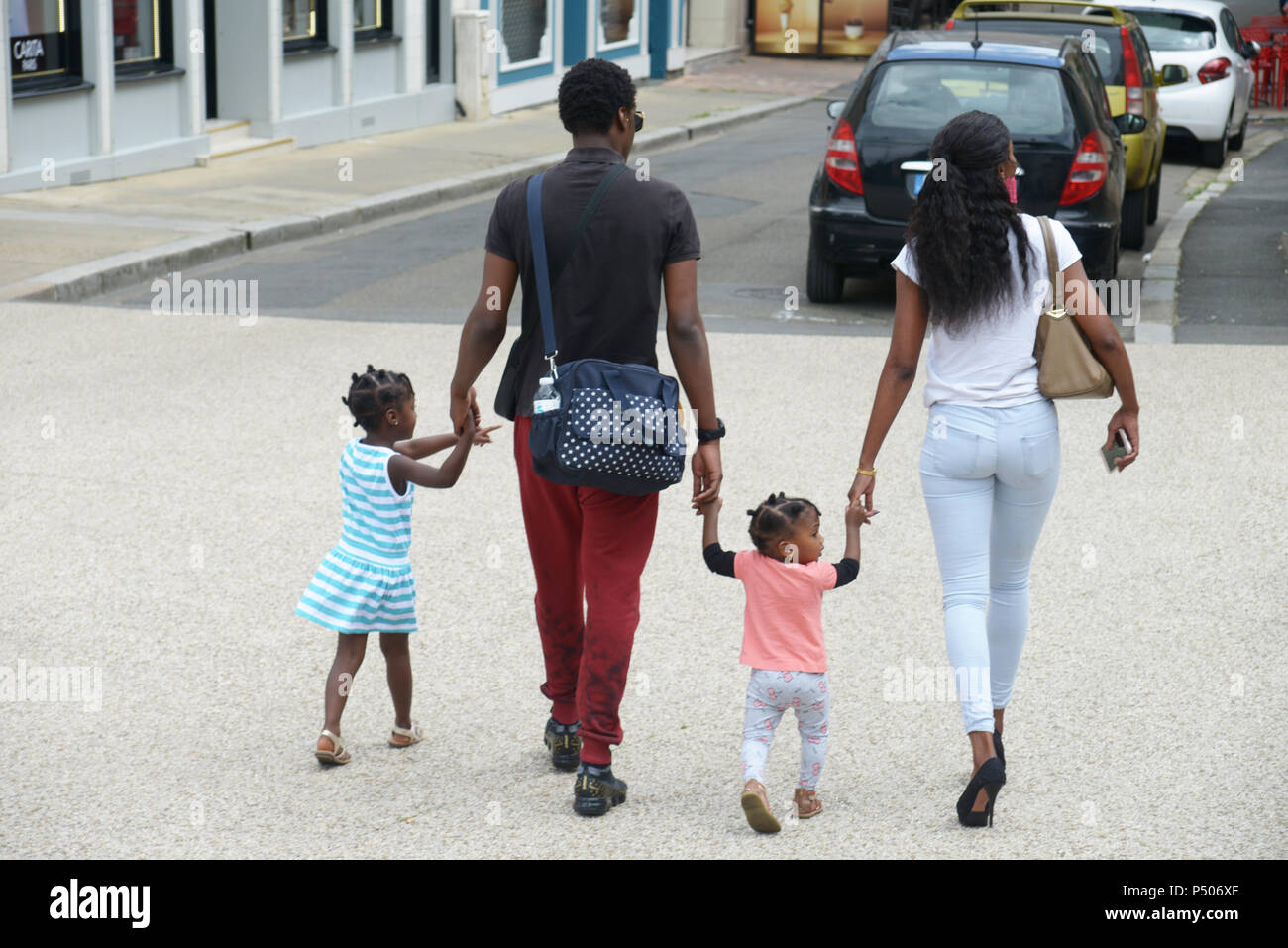 Happy young family walking through the quiet sunday streets Le Mans ...