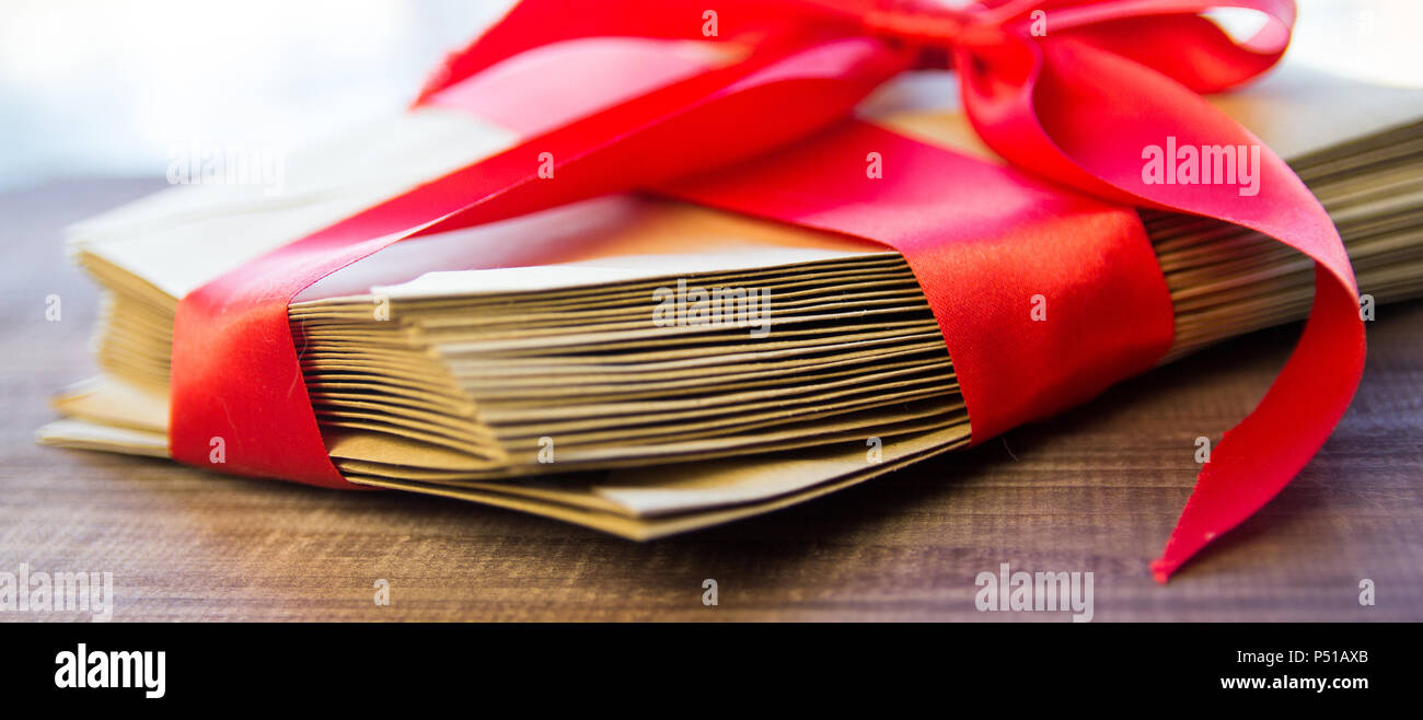 Old letters tied with a red ribbon on old wooden background, top view ...